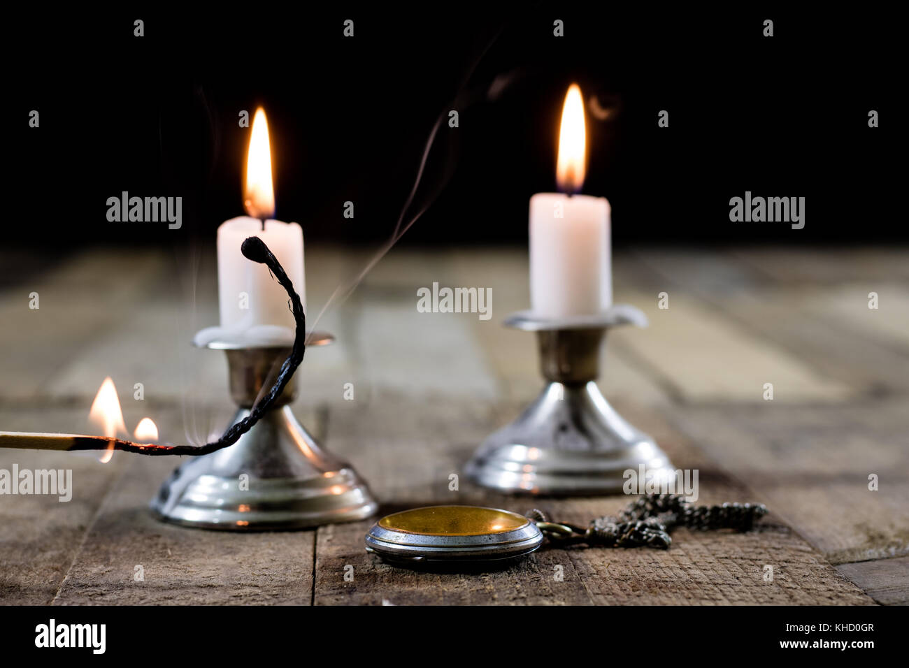 candles burning in candlesticks on a wooden table. Silver candlesticks ...