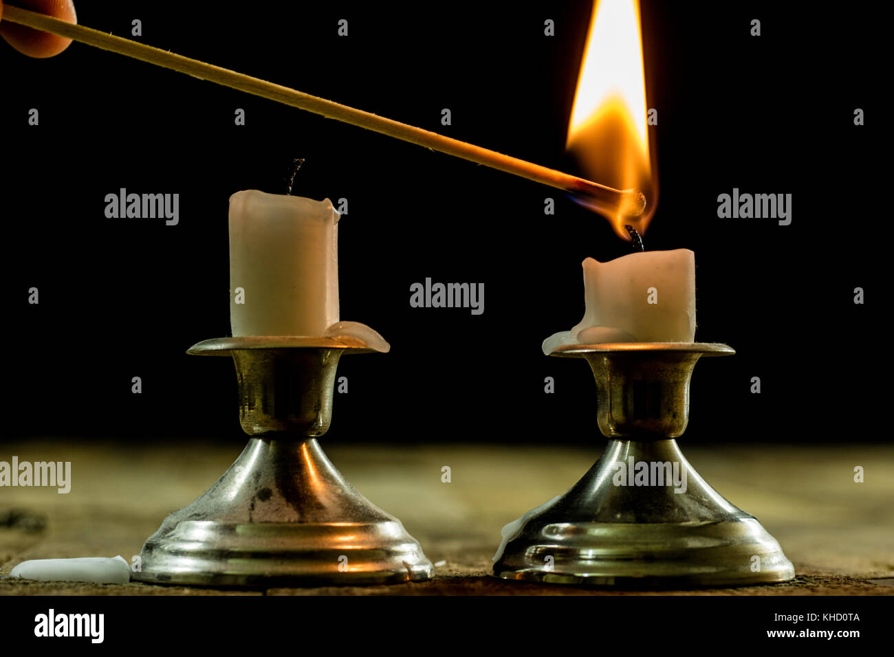 candles burning in candlesticks on a wooden table. Silver candlesticks ...