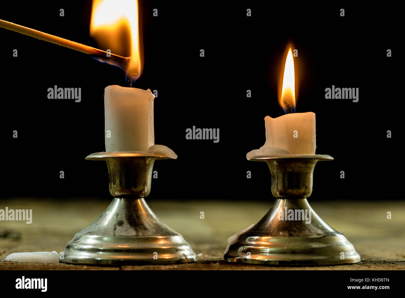 candles burning in candlesticks on a wooden table. Silver candlesticks ...