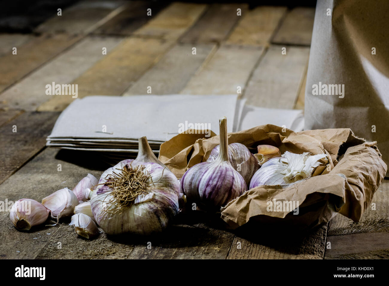 Garlic in a crumpled paper bag on a wooden table. Kitchen table with ...