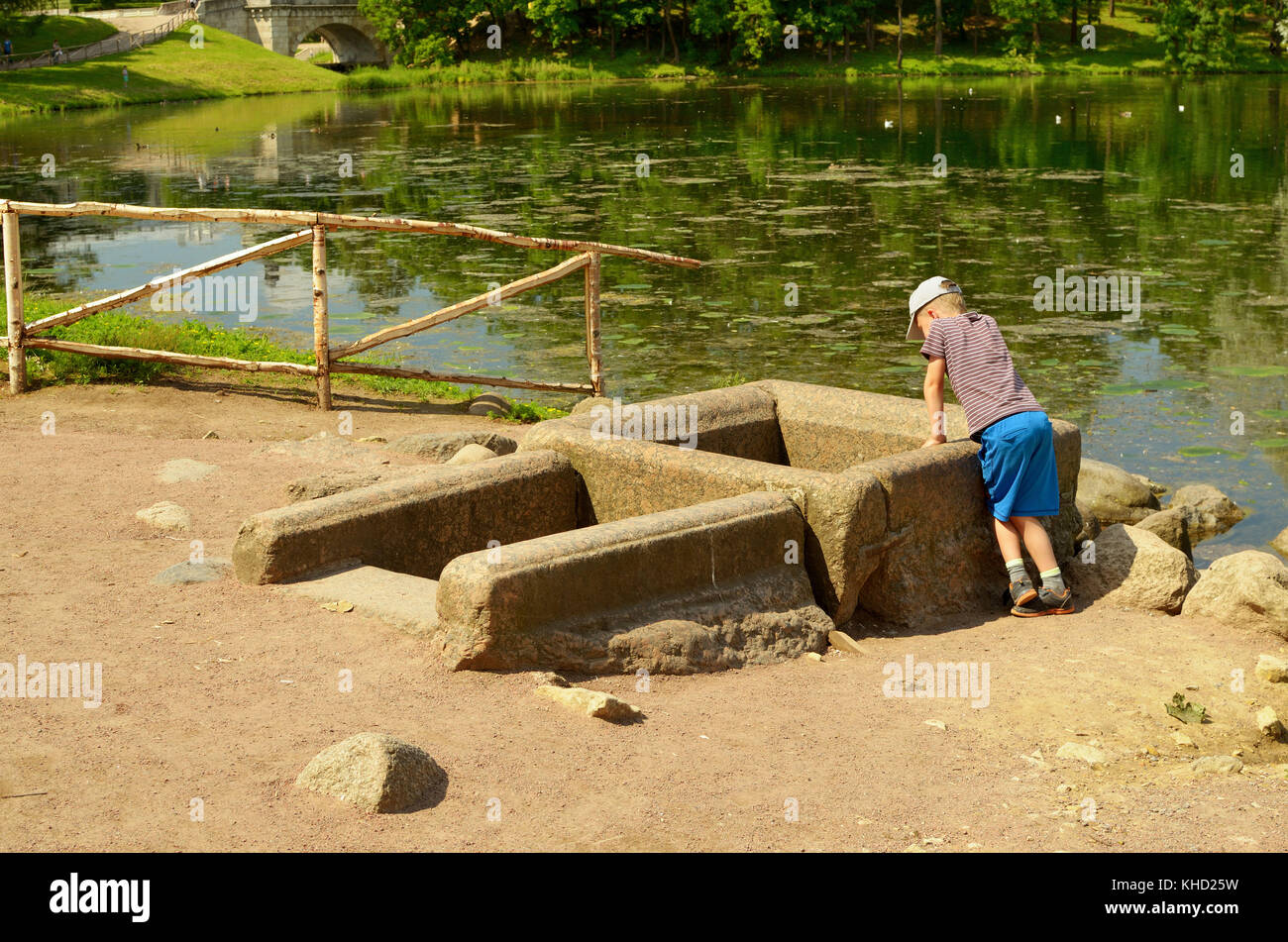 The boy looks inside the stone well,located in the Park Stock Photo - Alamy