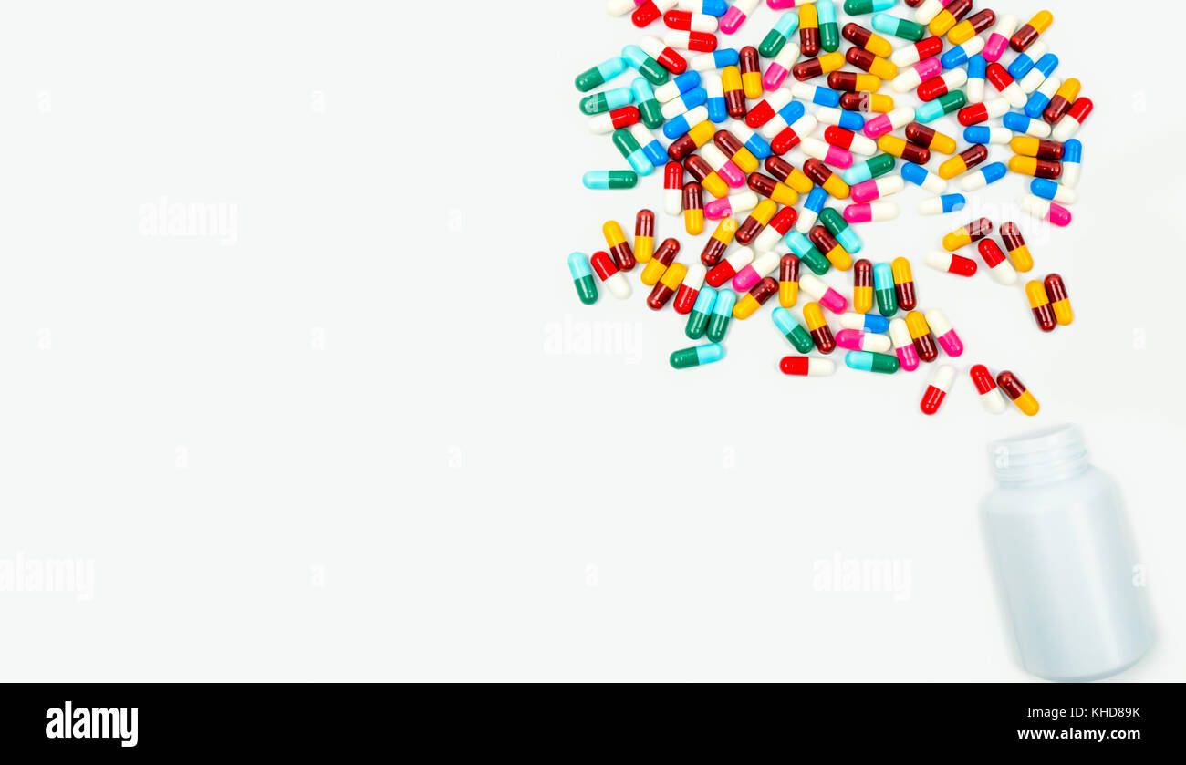 Pouring antibiotics capsule pills into plastic bottle isolated on white ...