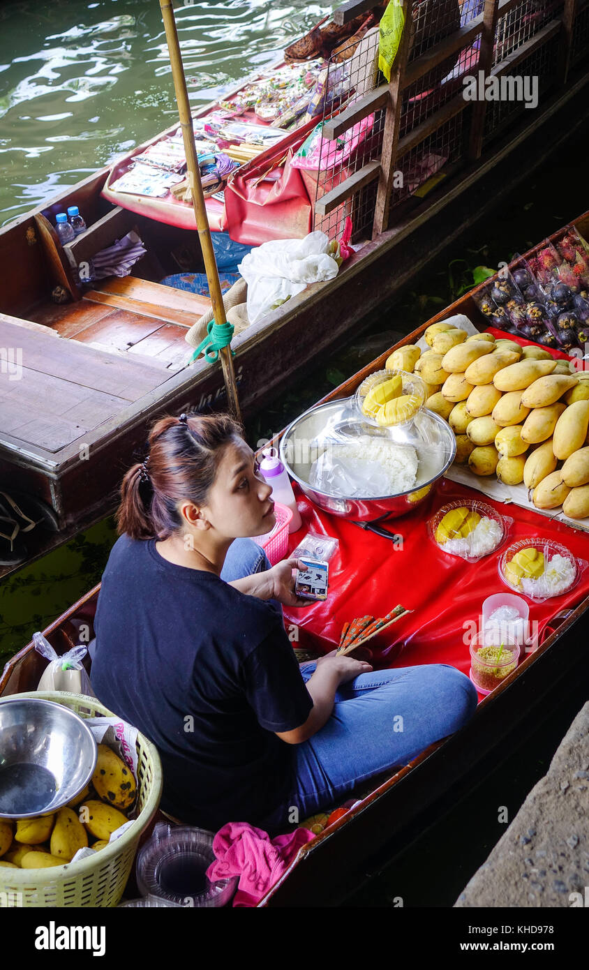 Bangkok, Thailand - Jun 19, 2017. A woman selling mangoes at Damnoen ...