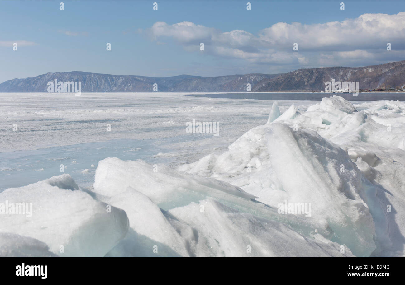 Transparent blue ice hummocks on lake Baikal shore. Siberia winter landscape view. Snow-covered ...
