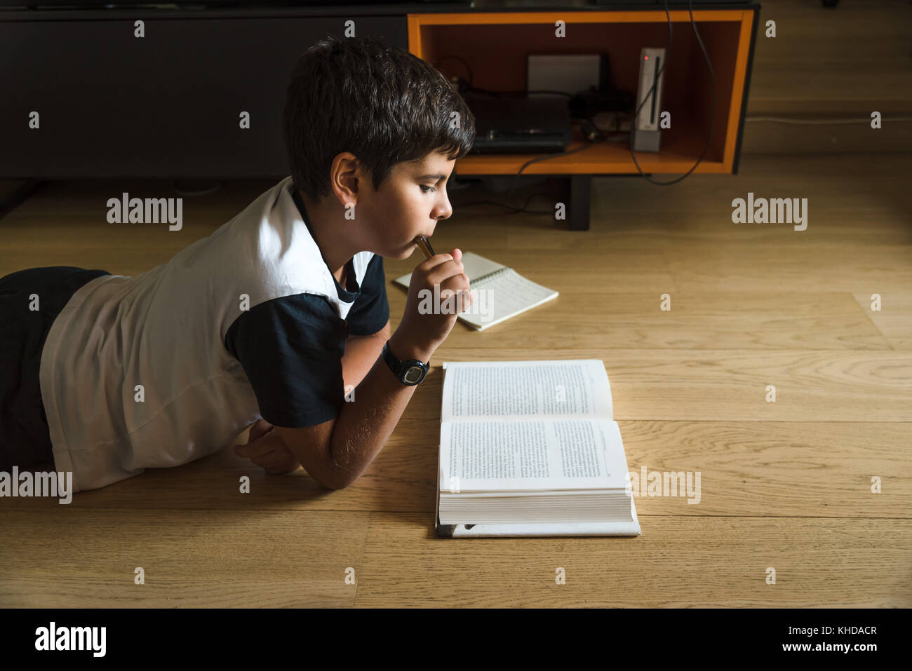 Little boy child reading a book. He lies on the floor Stock Photo - Alamy
