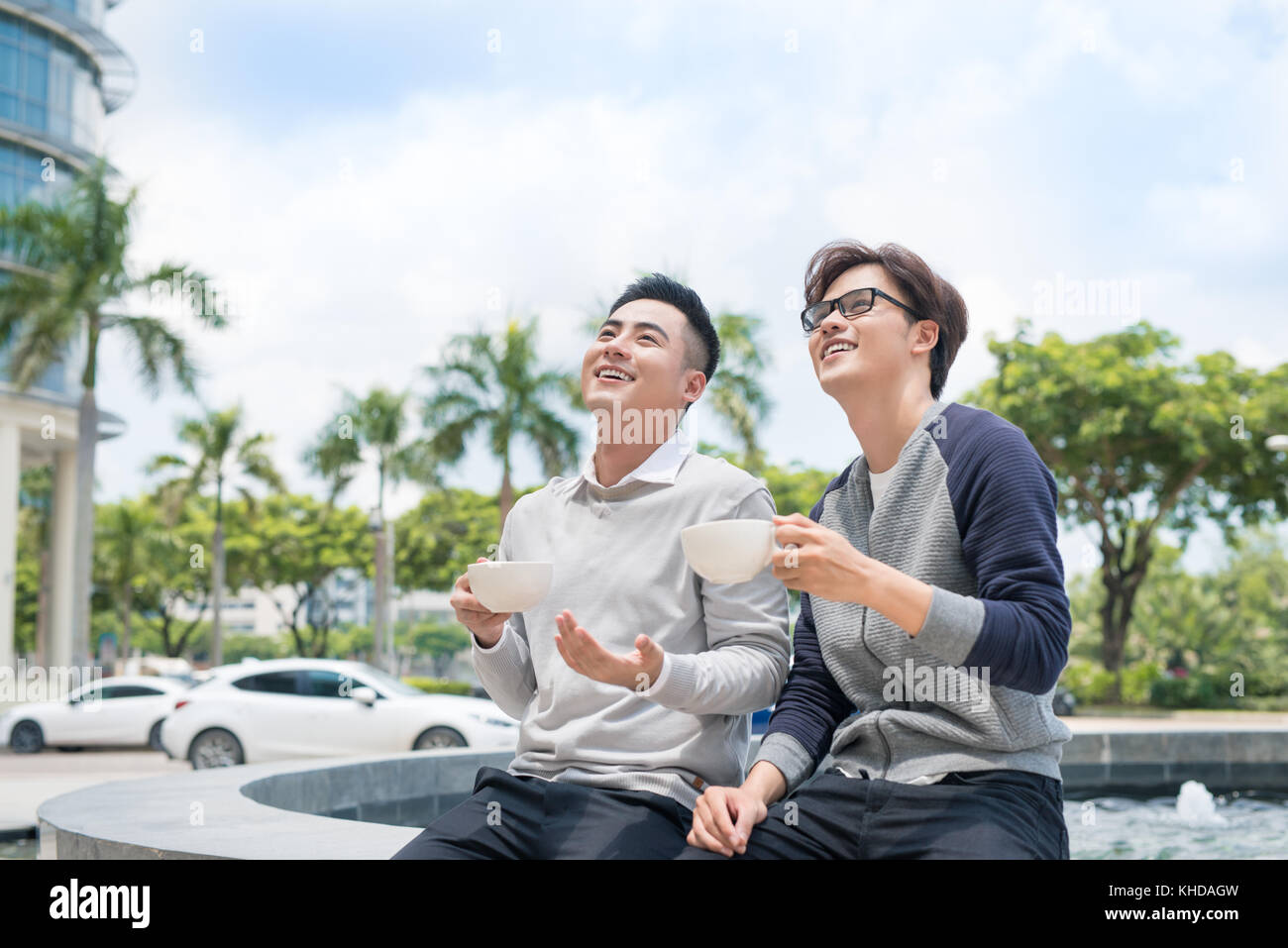 Two adult male friends sit talking over coffee outside cafe Stock Photo ...