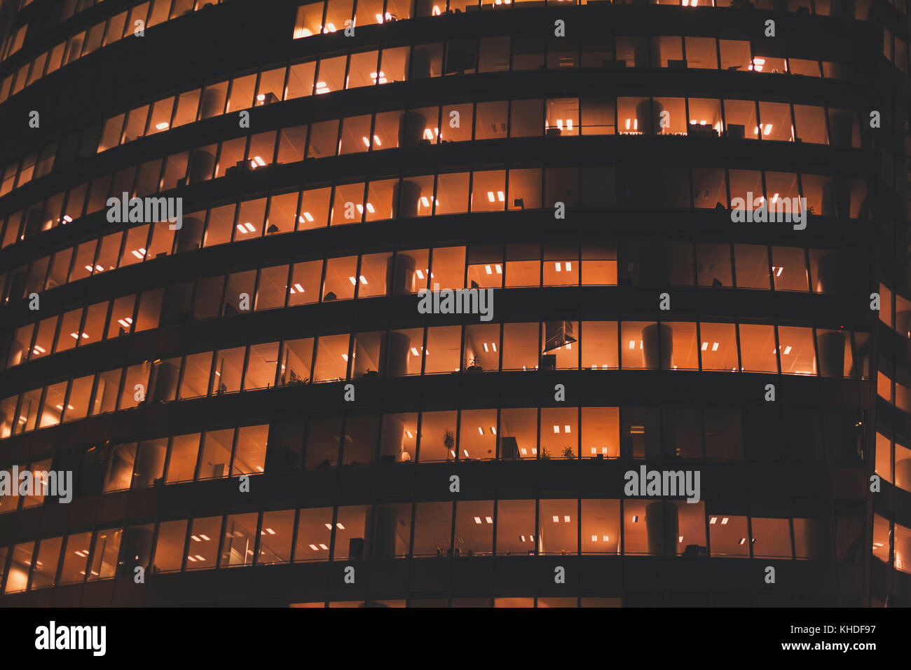 yellow light in windows of office building by night, business tower ...