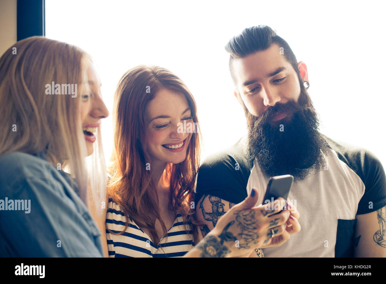 Friends looking at smartphone together Stock Photo - Alamy