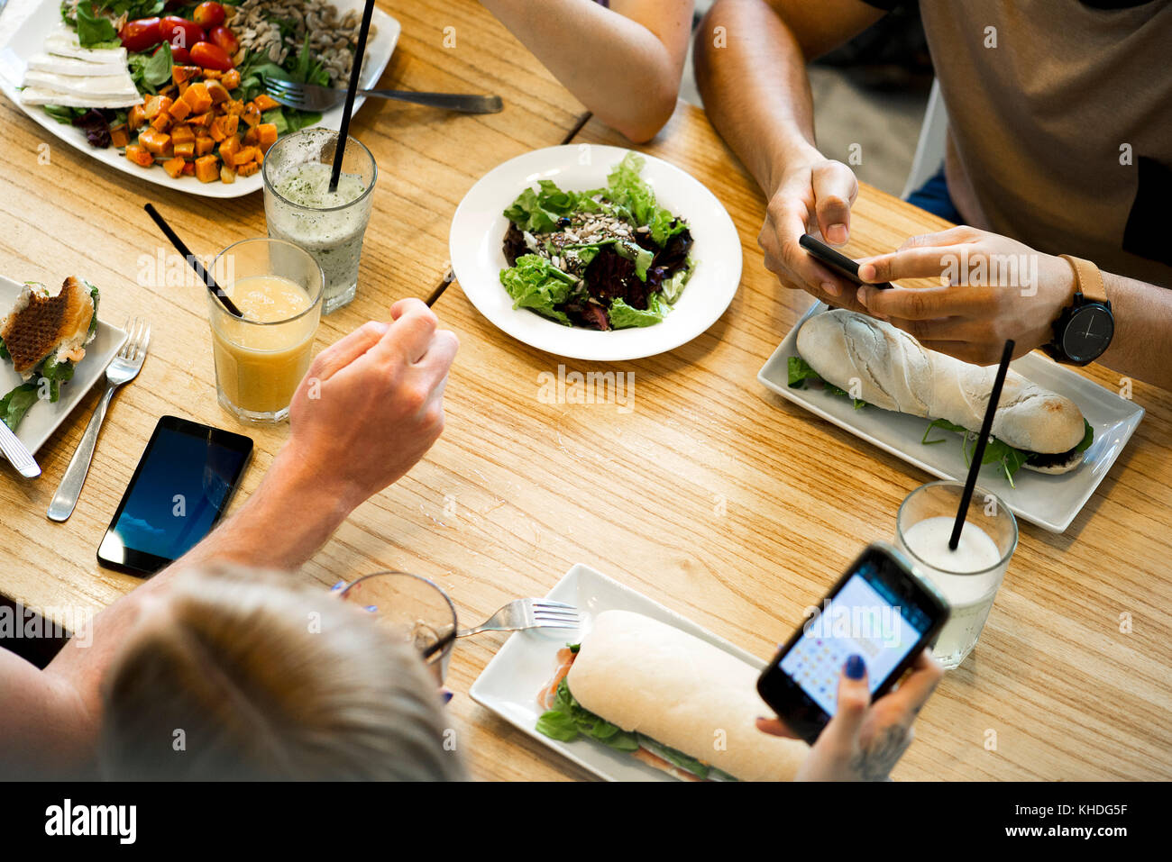 Friends using smartphones while eating in restaurant Stock Photo - Alamy