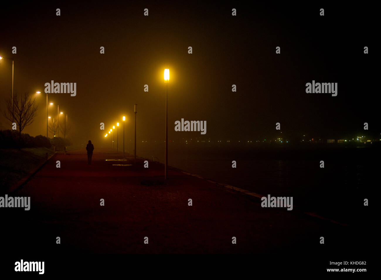 Person walking along deserted waterfront at night Stock Photo - Alamy