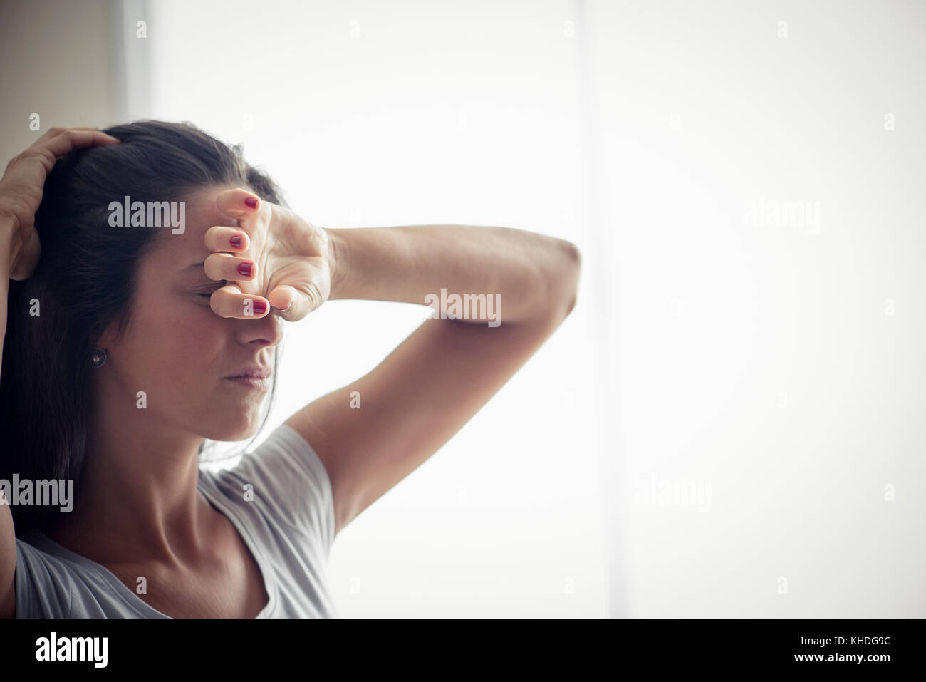 Young woman holding one hand on forehead Stock Photo - Alamy