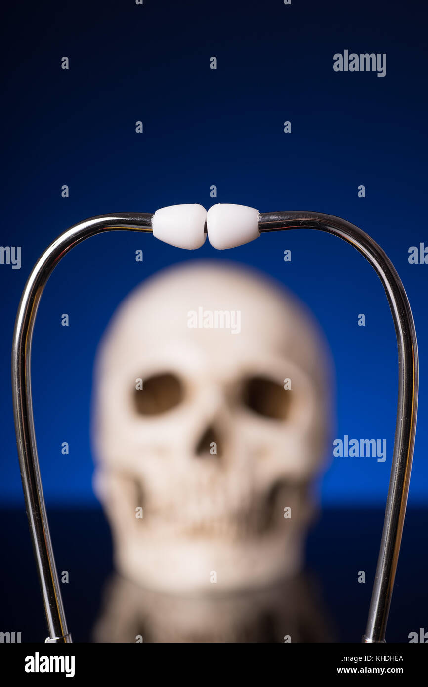 Stethoscope i focus and blurry skull isolated on black blue background ...