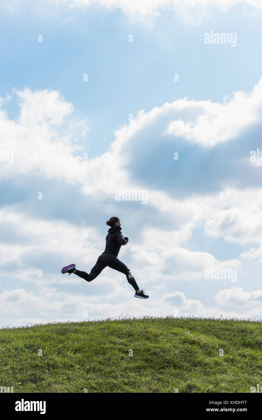 sporty woman jumping on hill Stock Photo - Alamy
