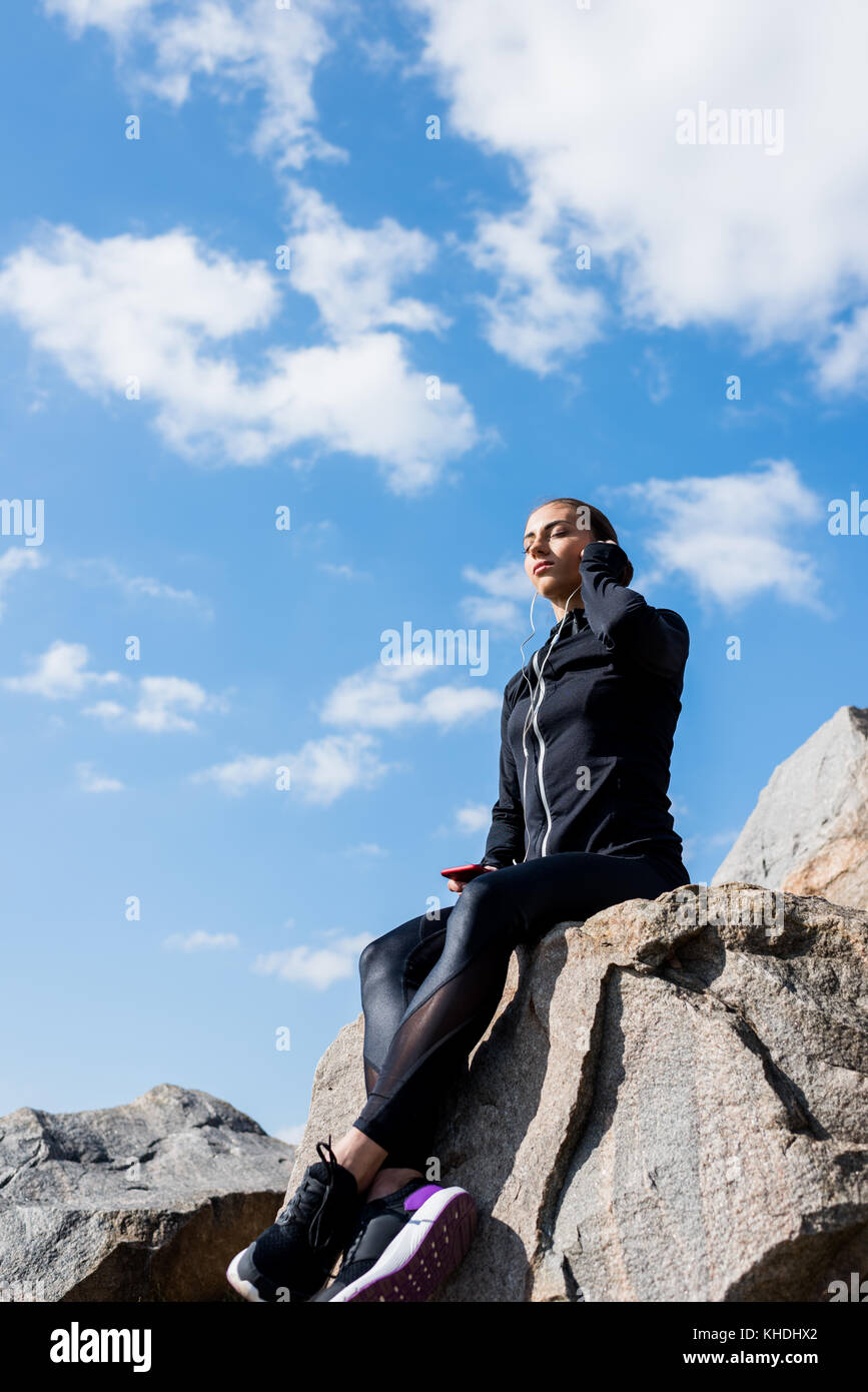 woman sitting on rocks and listening music Stock Photo - Alamy