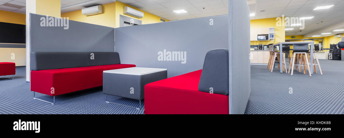 Panorama of library lounge area with red sofa, table and grey partition ...