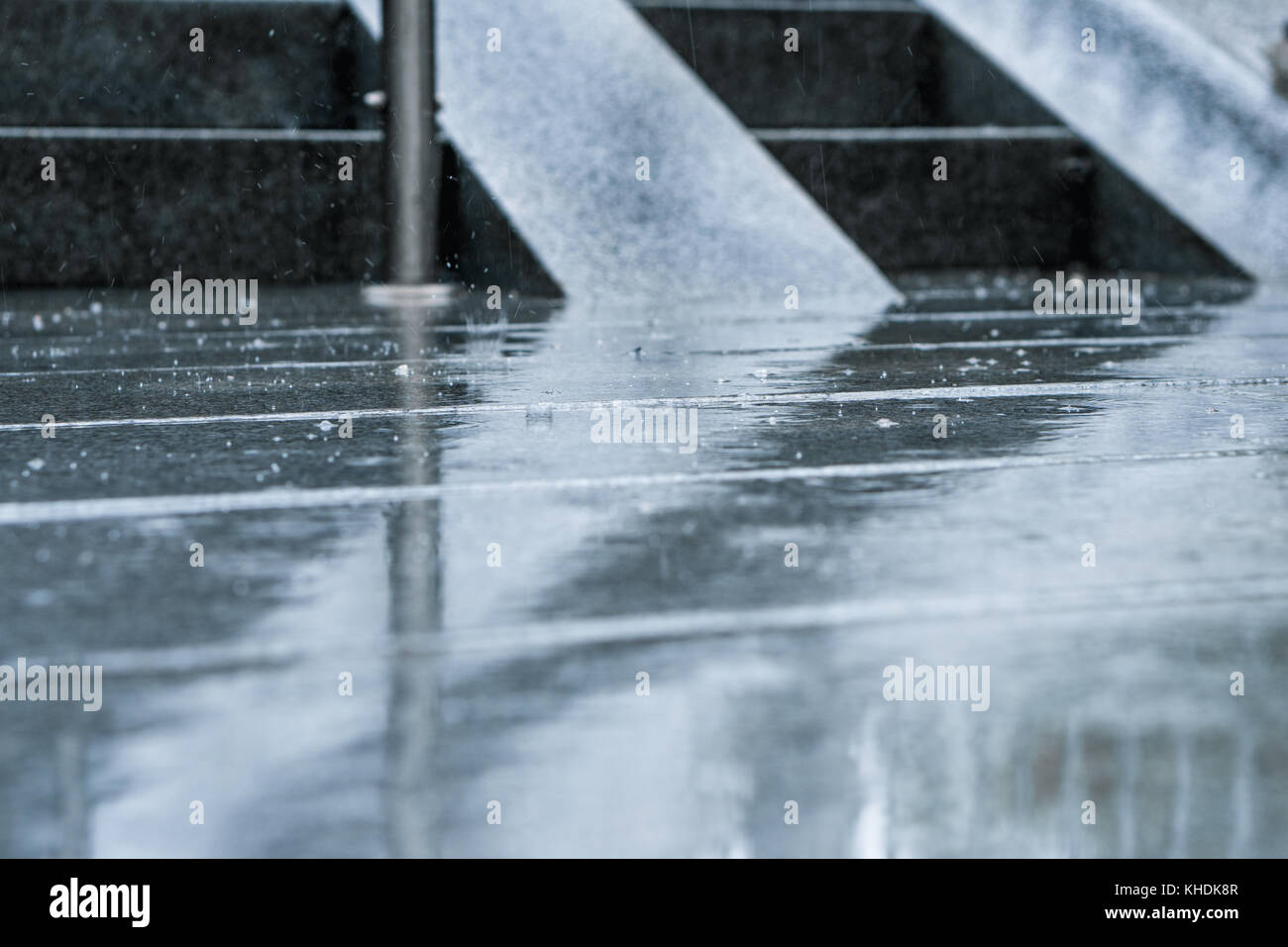 Heavy rain drops falling on city street with stairs in the background ...