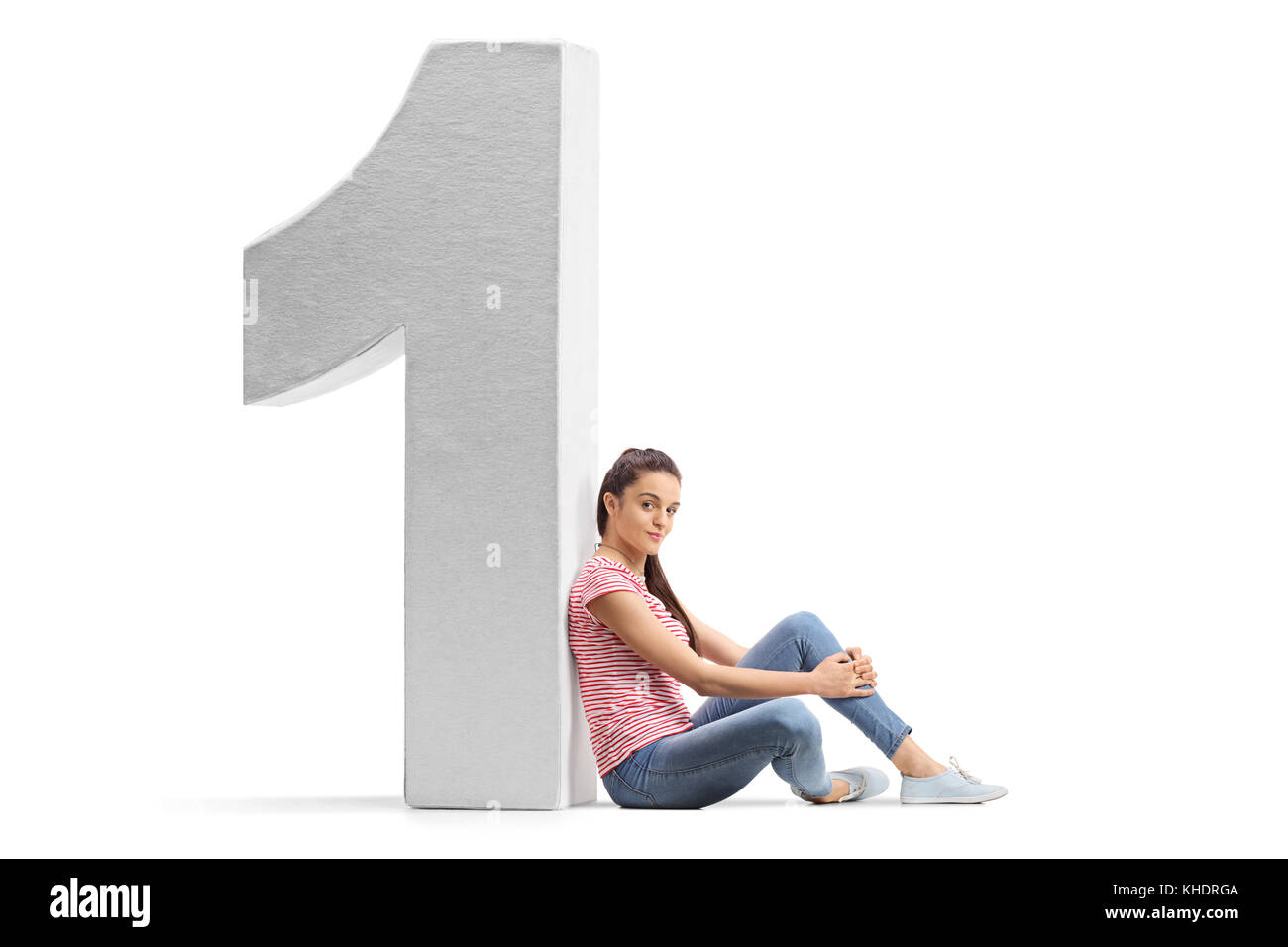 Teenage girl leaning against a cardboard number one isolated on white ...