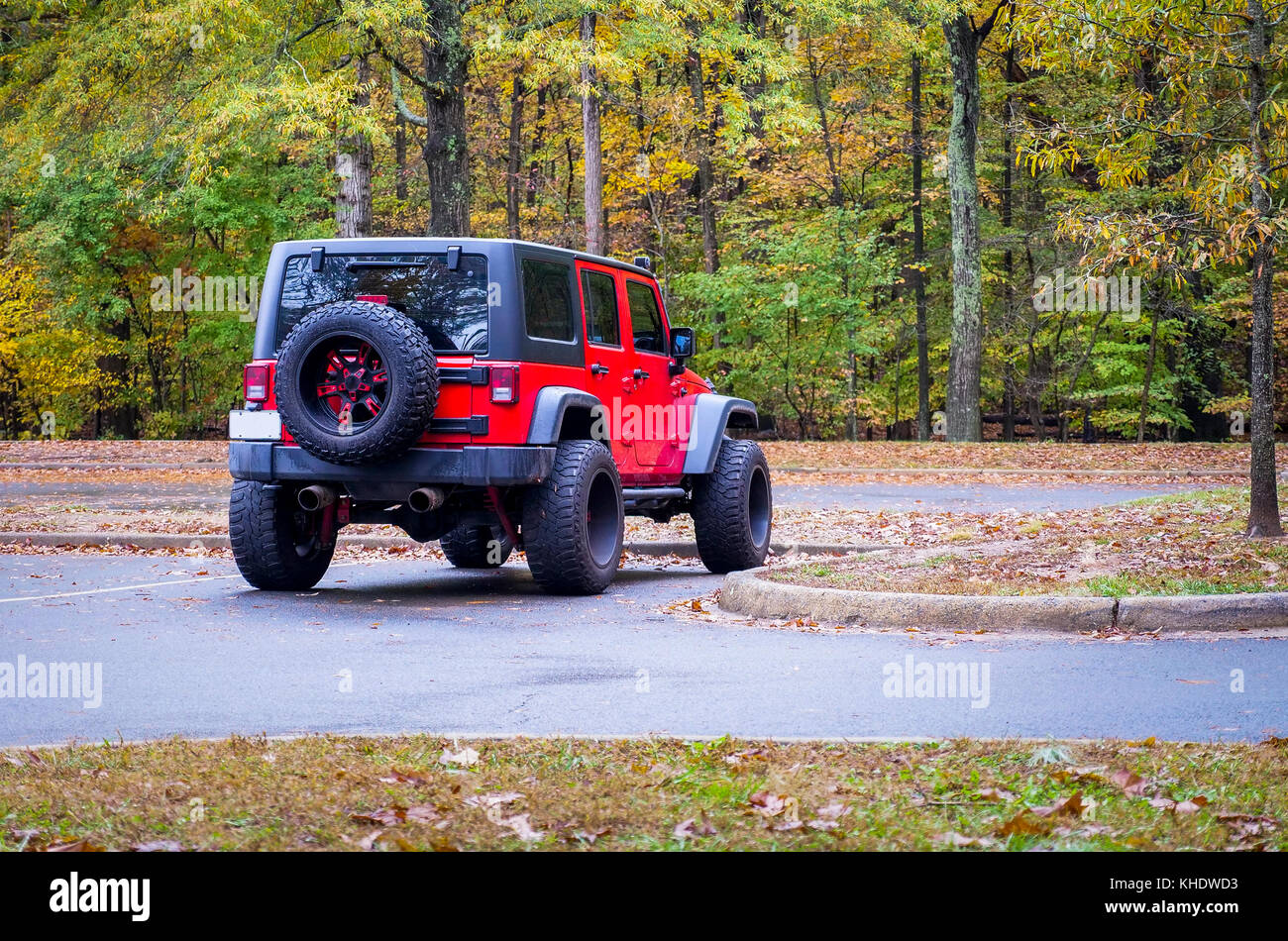 Red 4WD all-terrain vehicle parked in a parking lot in autumn woodland ...