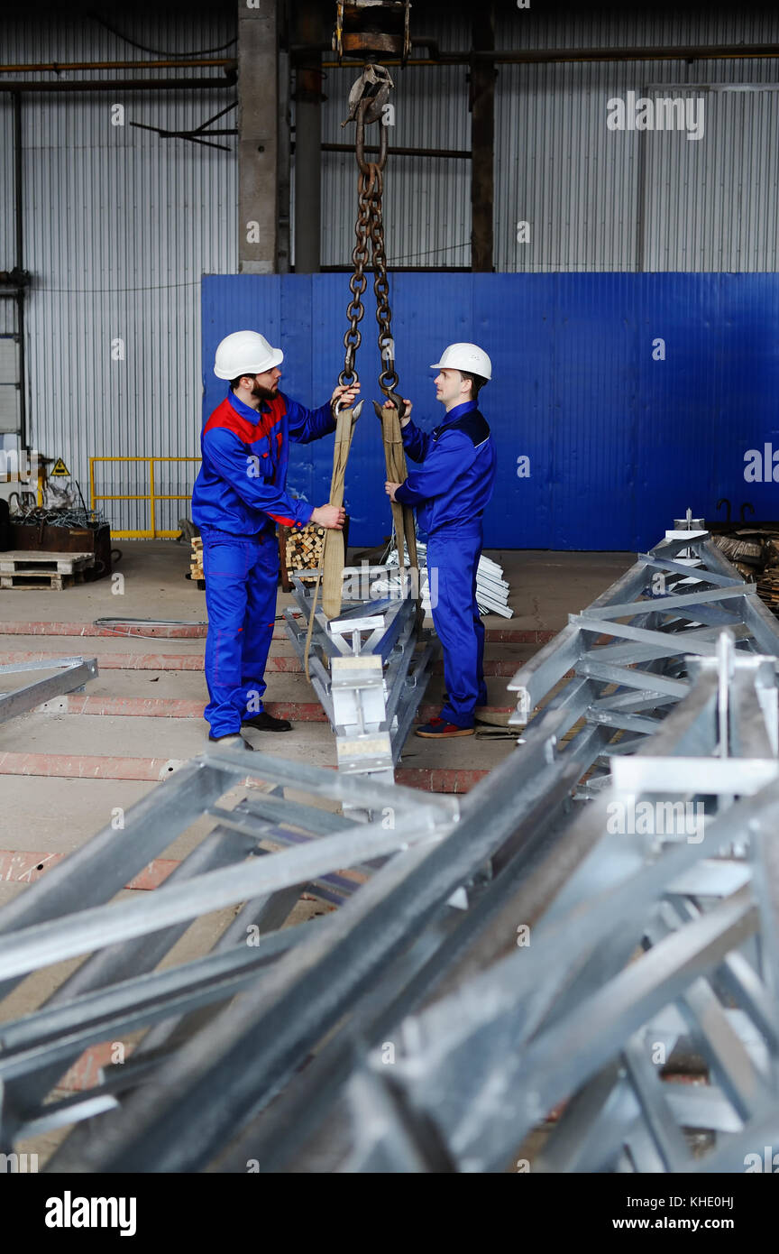Workers at the plant load the cargo onto the hook of the crane against ...