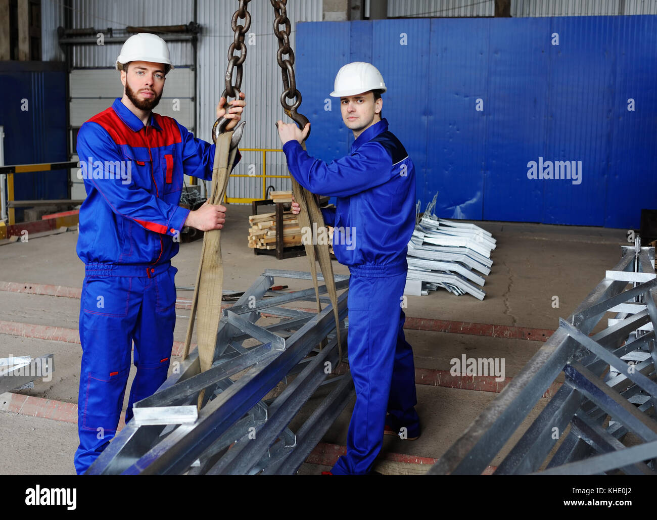 Two workers load industrial products onto the crane hook Stock Photo ...