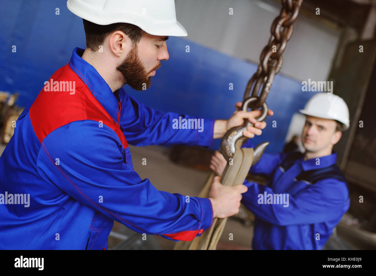 Two workers load industrial products onto the crane hook Stock Photo ...