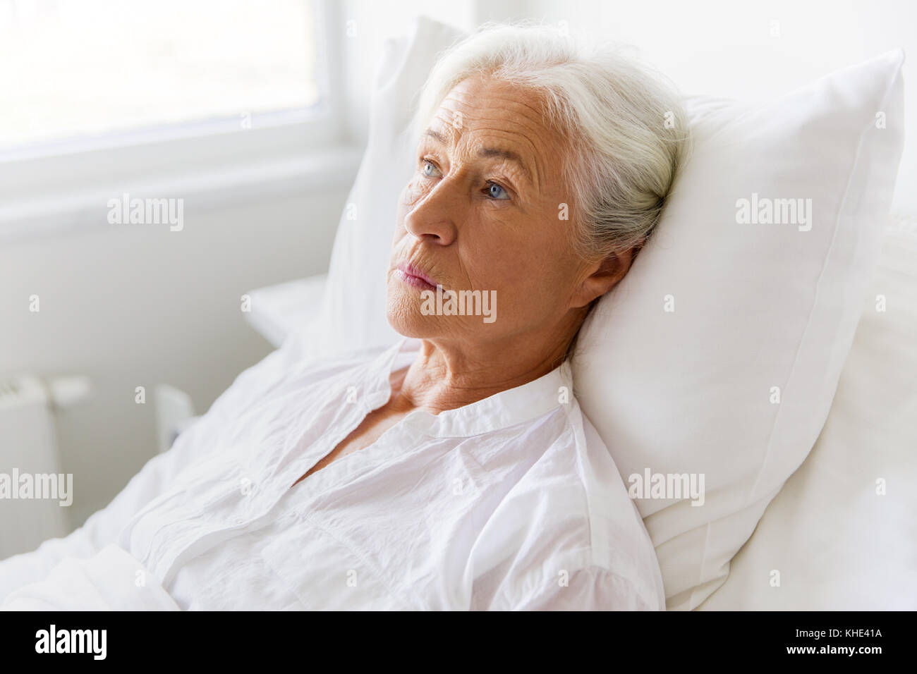 sad senior woman lying on bed at hospital ward Stock Photo - Alamy