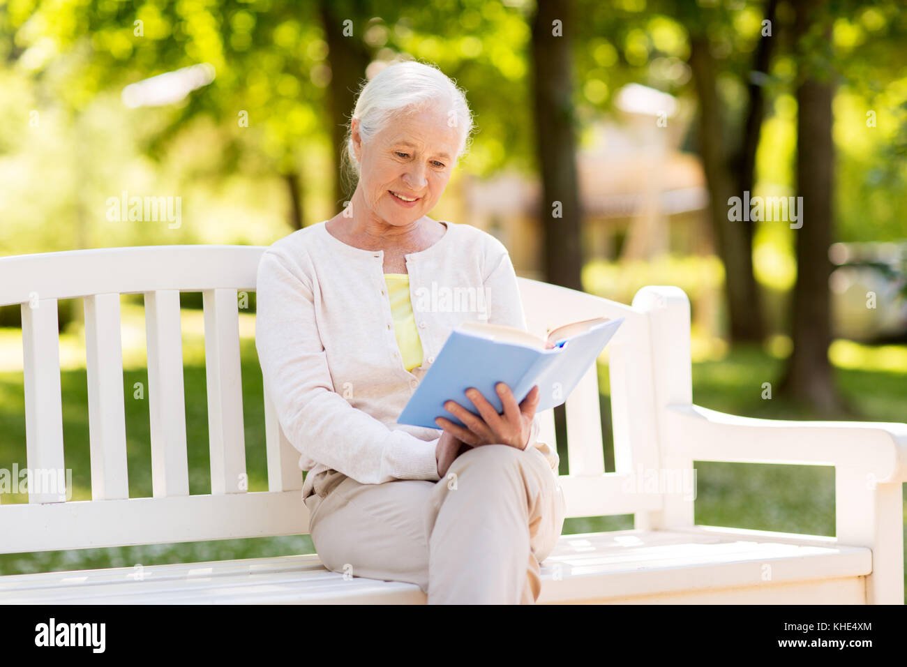 happy senior woman reading book at summer park Stock Photo - Alamy