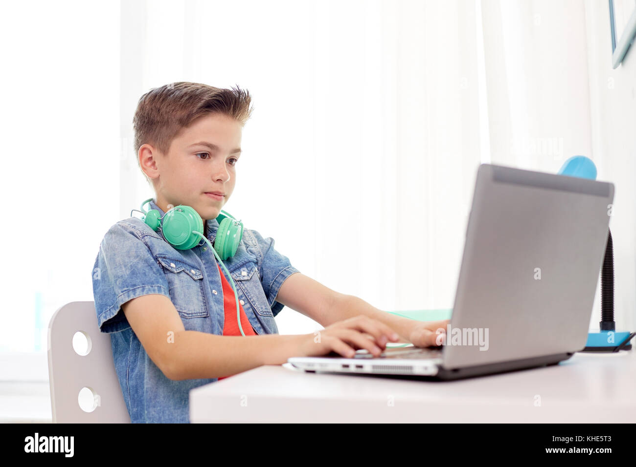 happy boy with headphones typing on laptop at home Stock Photo - Alamy