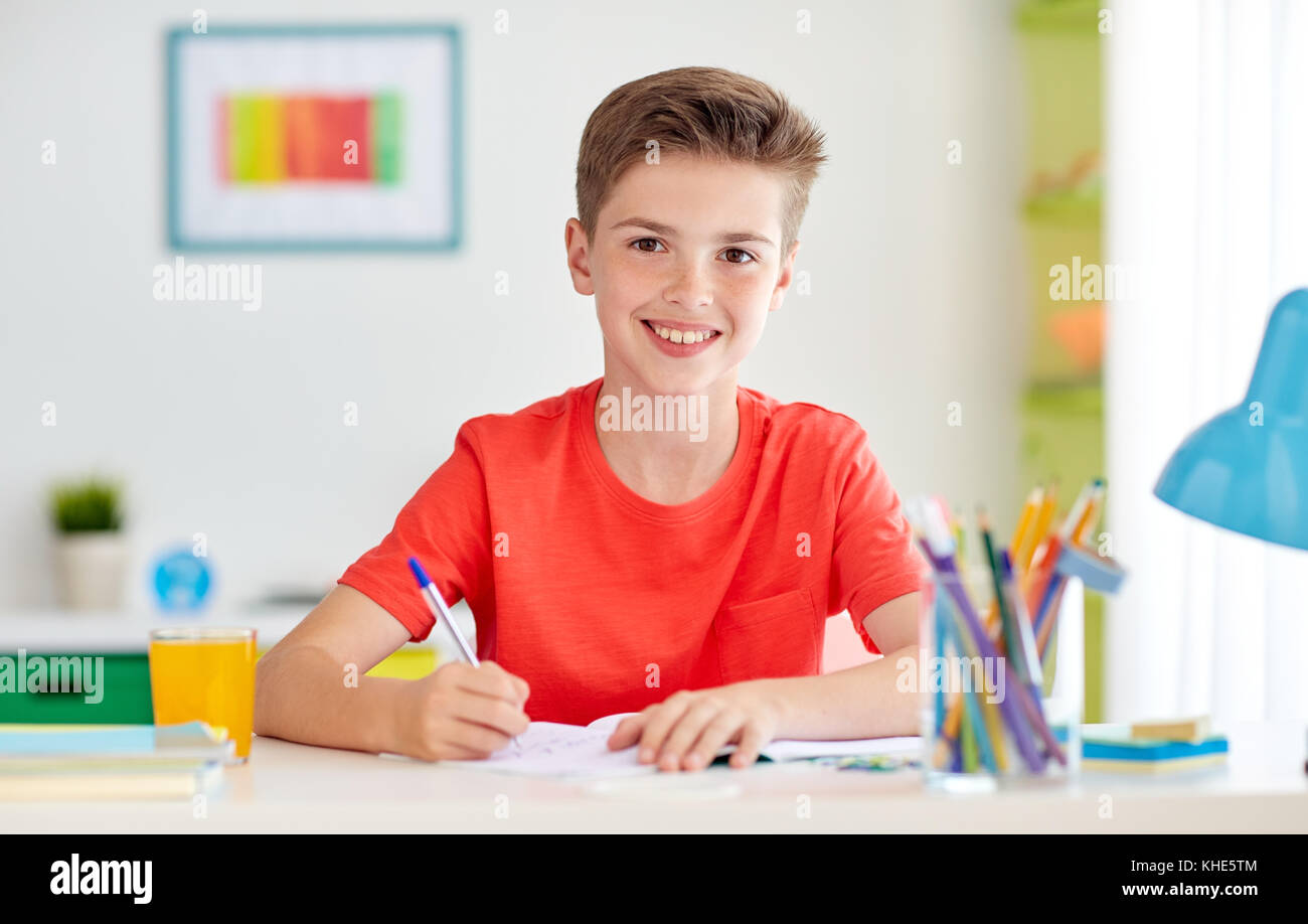 happy student boy writing to notebook at home Stock Photo - Alamy