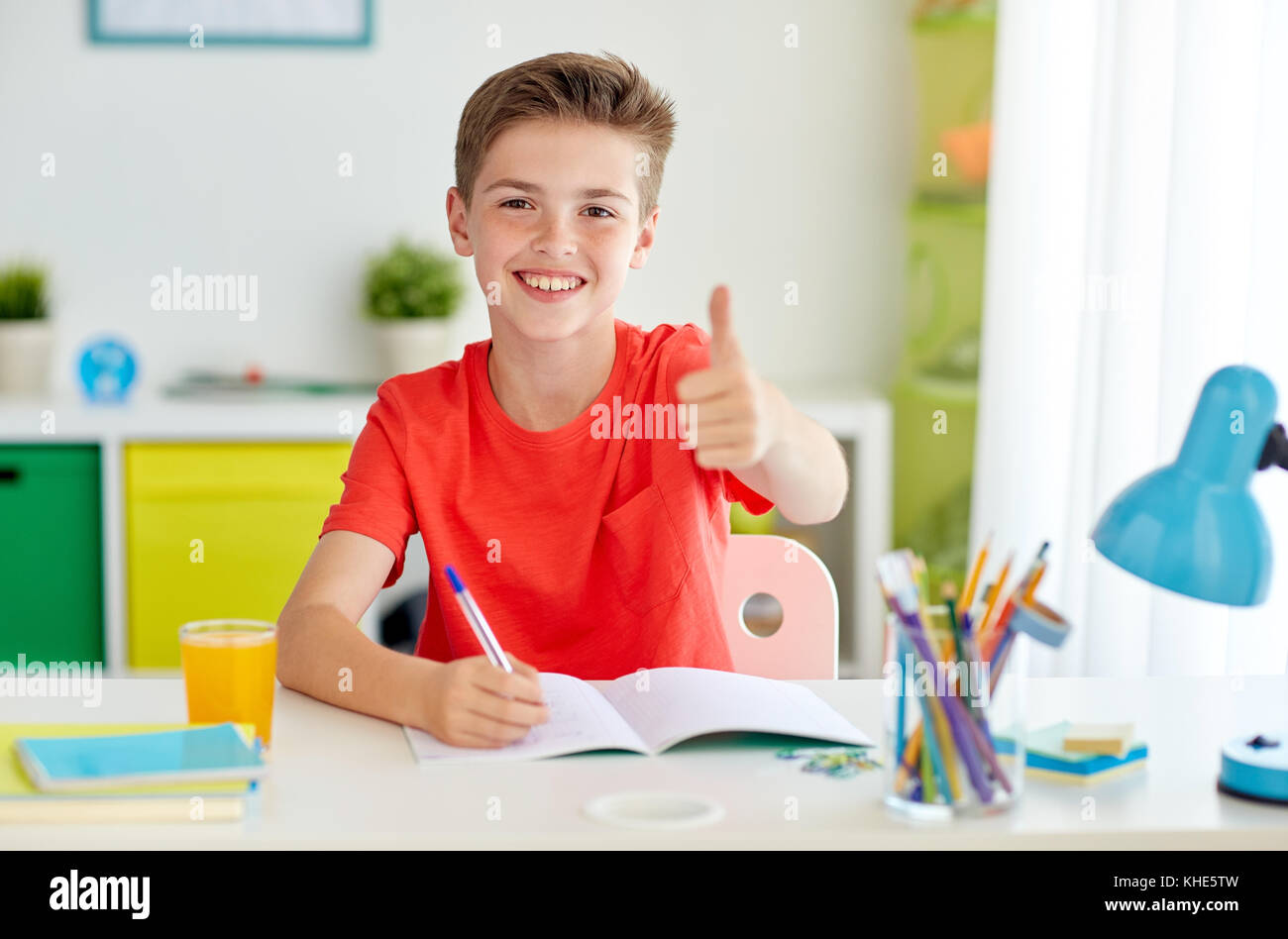 happy student boy writing to notebook at home Stock Photo - Alamy