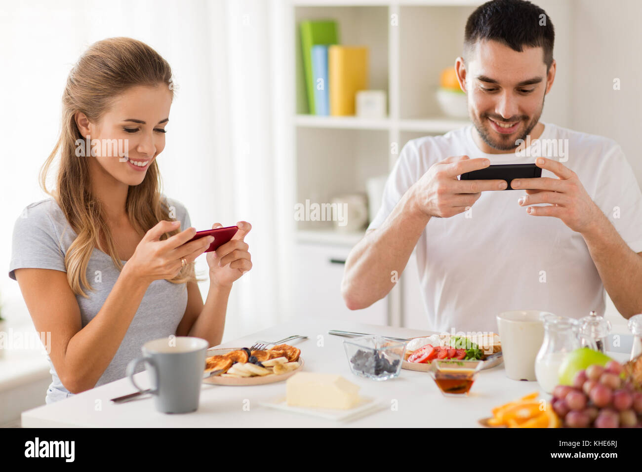 couple with smartphones having breakfast at home Stock Photo - Alamy