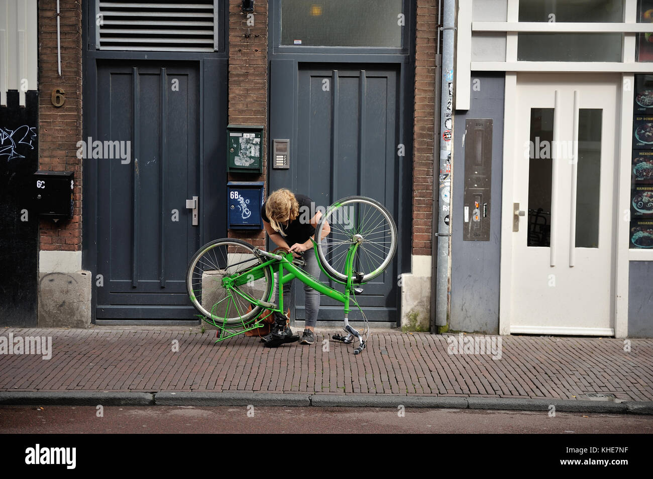 A woman fixes a bike on Amsterdam Street Stock Photo - Alamy