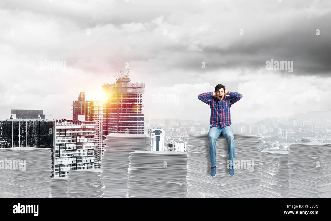 Attractive man sitting on pile of paper documents Stock Photo - Alamy