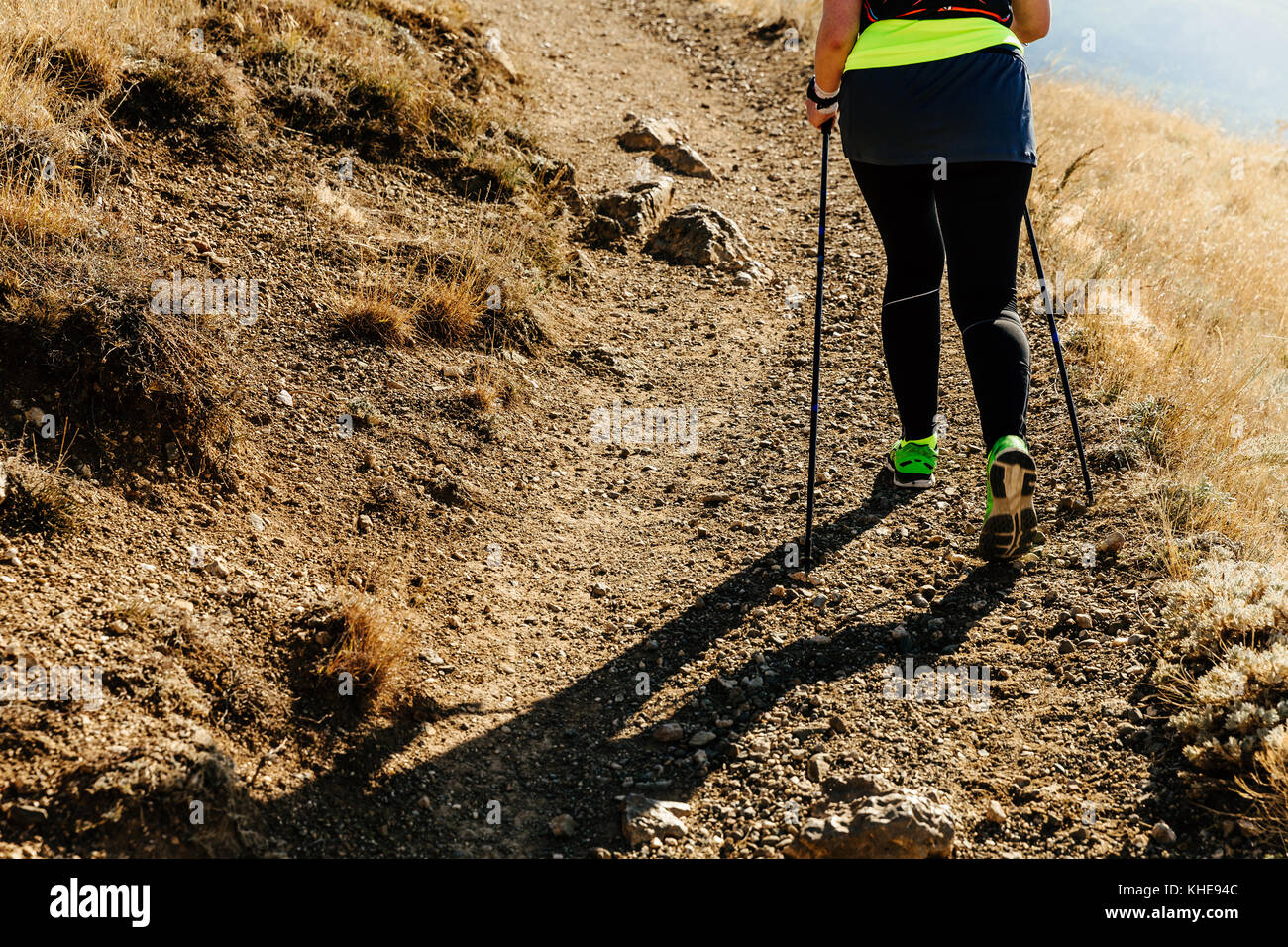 back woman walking on mountain trail with trekking poles Stock Photo ...