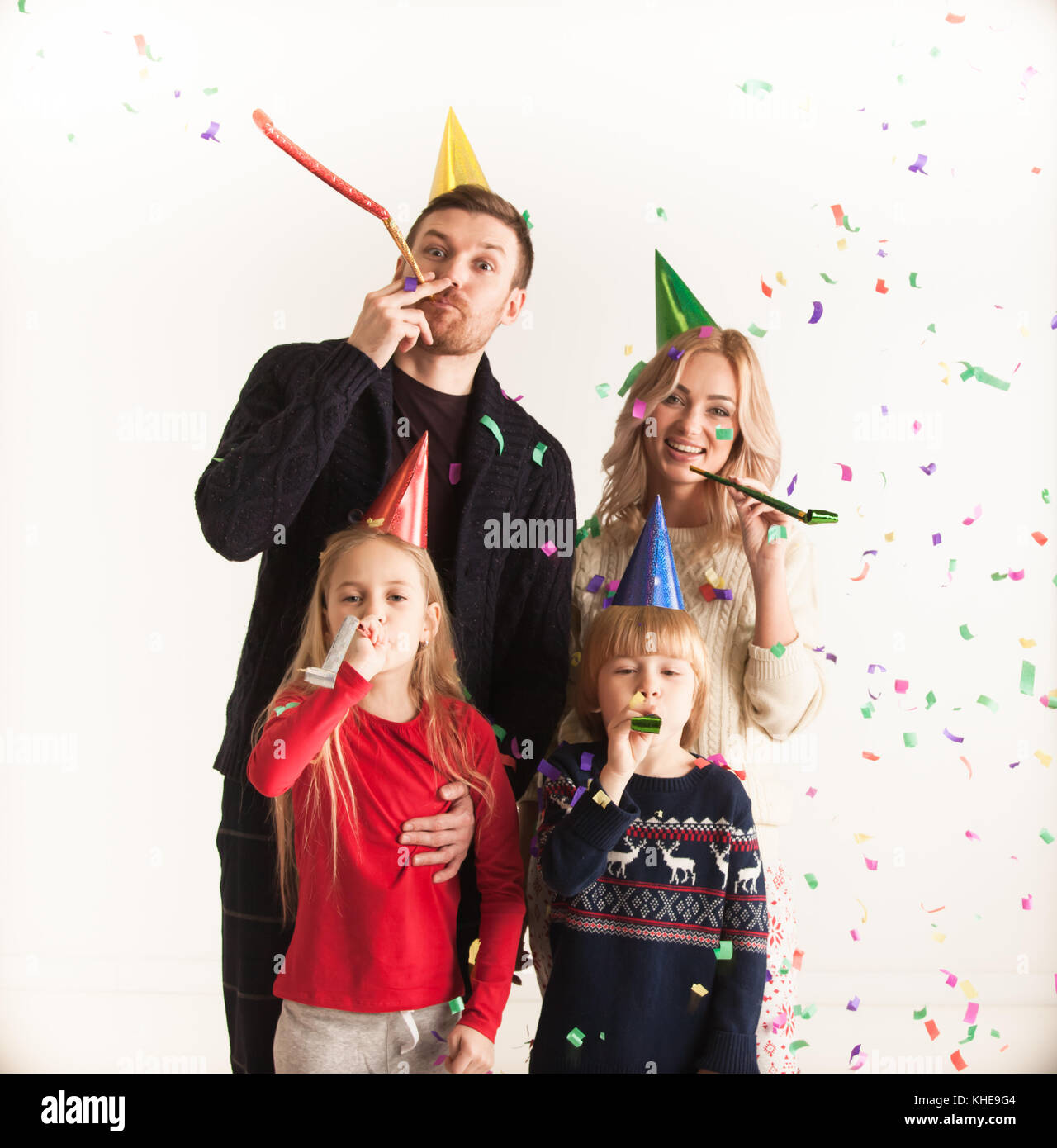 Family blowing party trumpets with confetti celebrating new year Stock ...