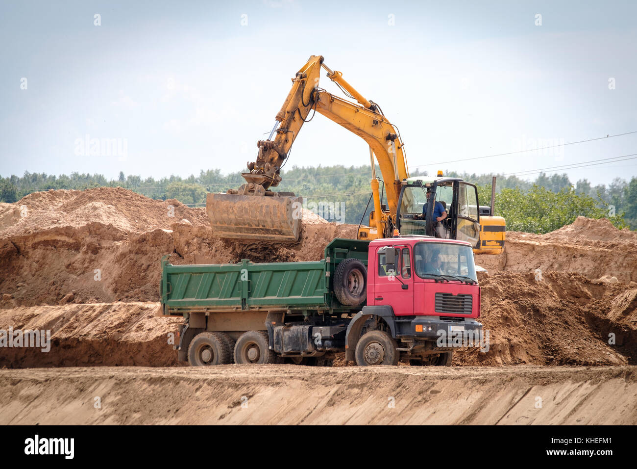 Excavator loads the ground in the truck Stock Photo - Alamy