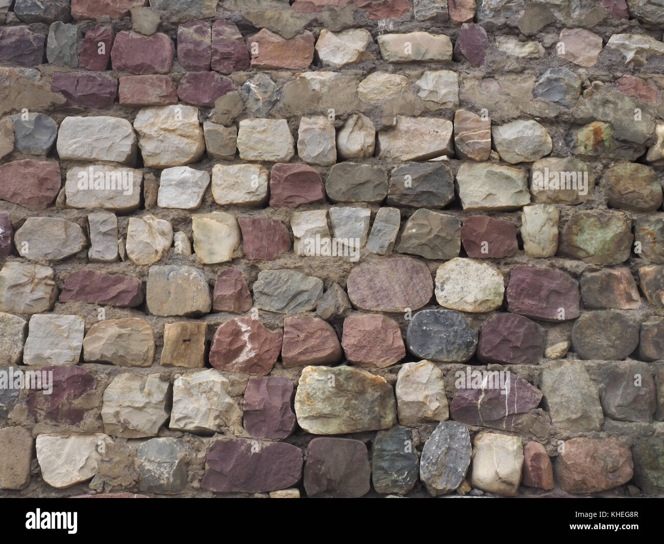 Rustic stone wall, masonry made of round and rectangular boulders, pink ...