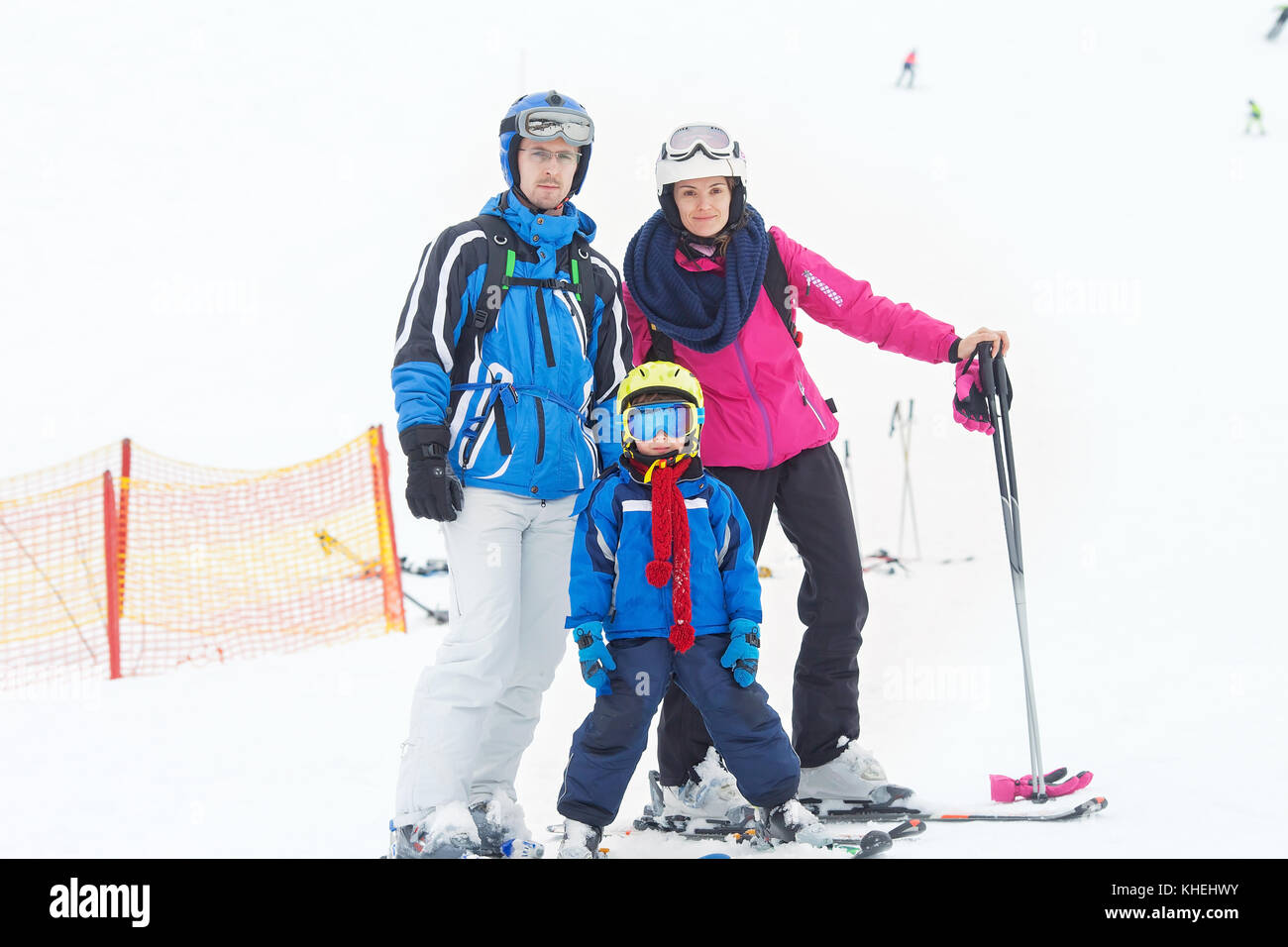 Young happy family with one child, skiing in the mountains, wintertime ...