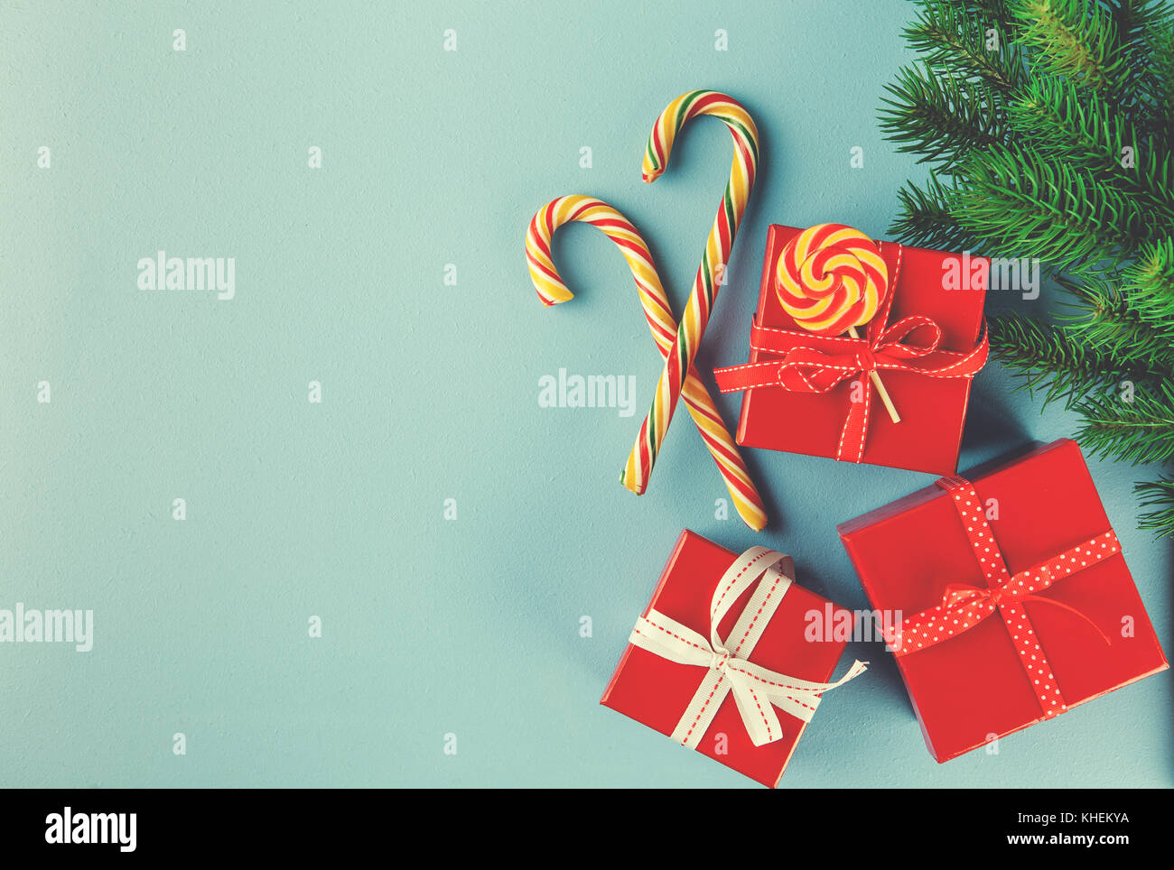 Christmas gift boxes, decorations, candy canes and fir tree branch on blue background. Flat lay ...
