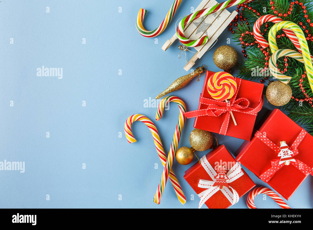 Christmas gift boxes, decorations, candy canes and fir tree branch on blue background. Flat lay ...
