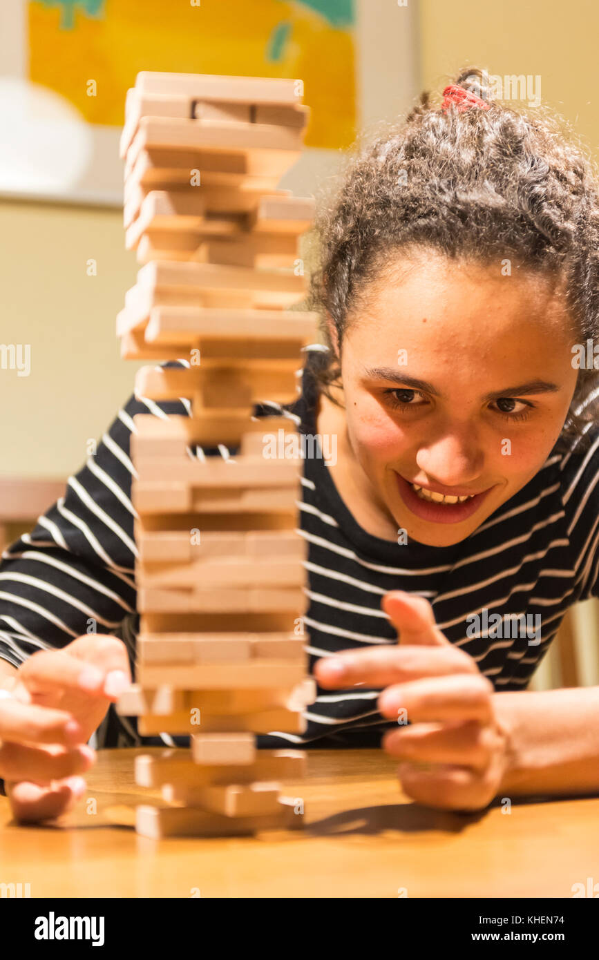 Young woman plays Jenga, stacking a tower with wooden blocks ...