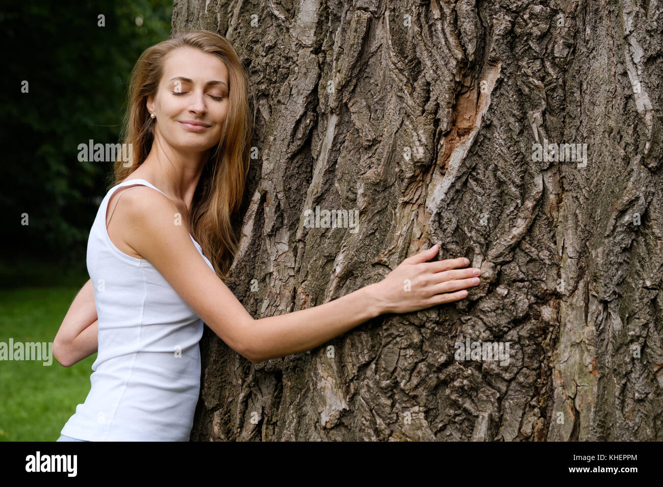 Young woman hugging big tree Stock Photo - Alamy