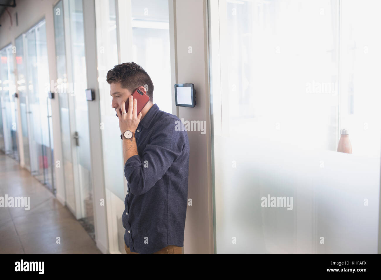 Young man talking on his smart phone in office hallway Stock Photo - Alamy
