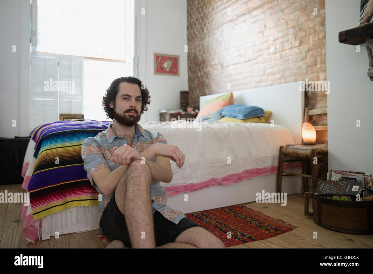 Young man sitting beside his bed Stock Photo - Alamy