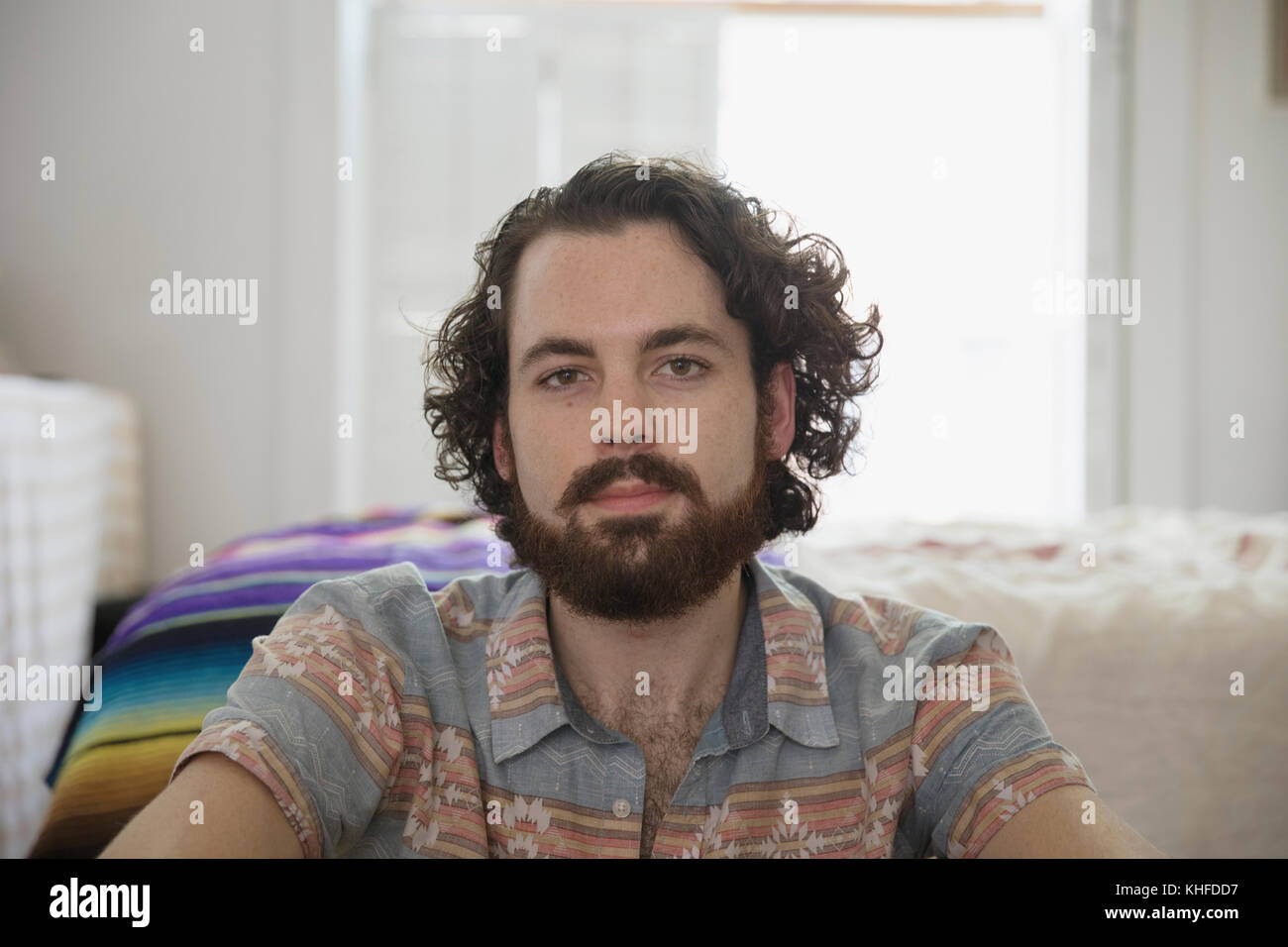 Young man sitting beside his bed Stock Photo - Alamy