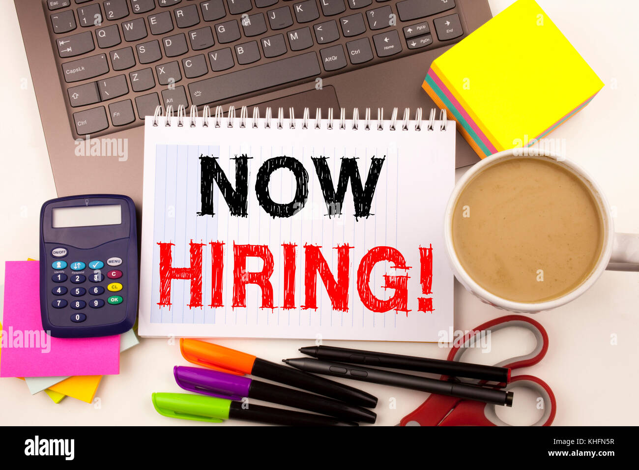 Now Hiring text in the office with surroundings such as laptop, marker ...