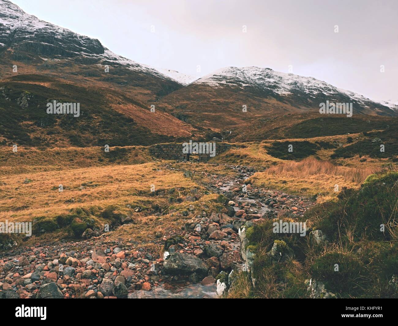 Stream and stony bridge in spring Hiigland mountains in Scotland. Snowy ...