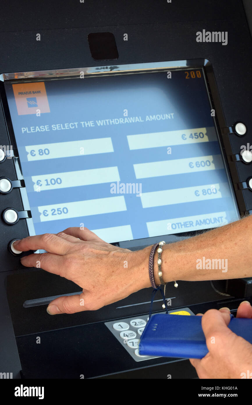 a womans hand using a cashpoint machine or a hole in the wall cash ...