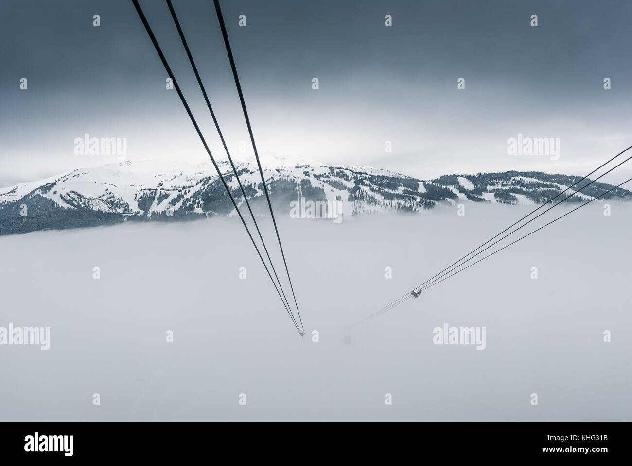 Cable car running between two snow covered mountains at a ski resort ...