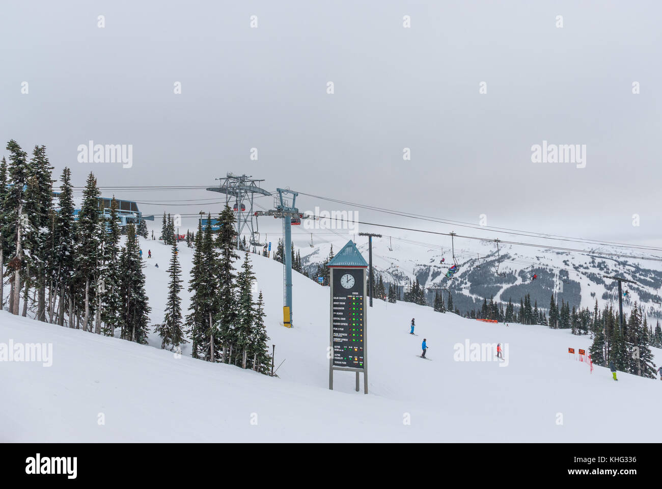 runs and lift status board with chairlift and skiiers in the background ...